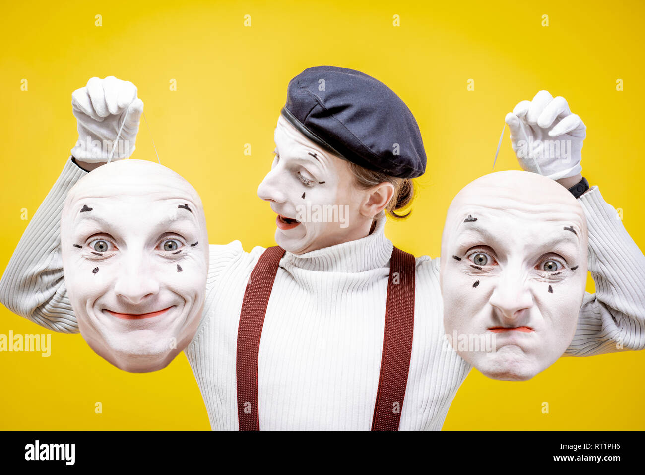 Portrait of a pantoomime holding two facial masks with different ...