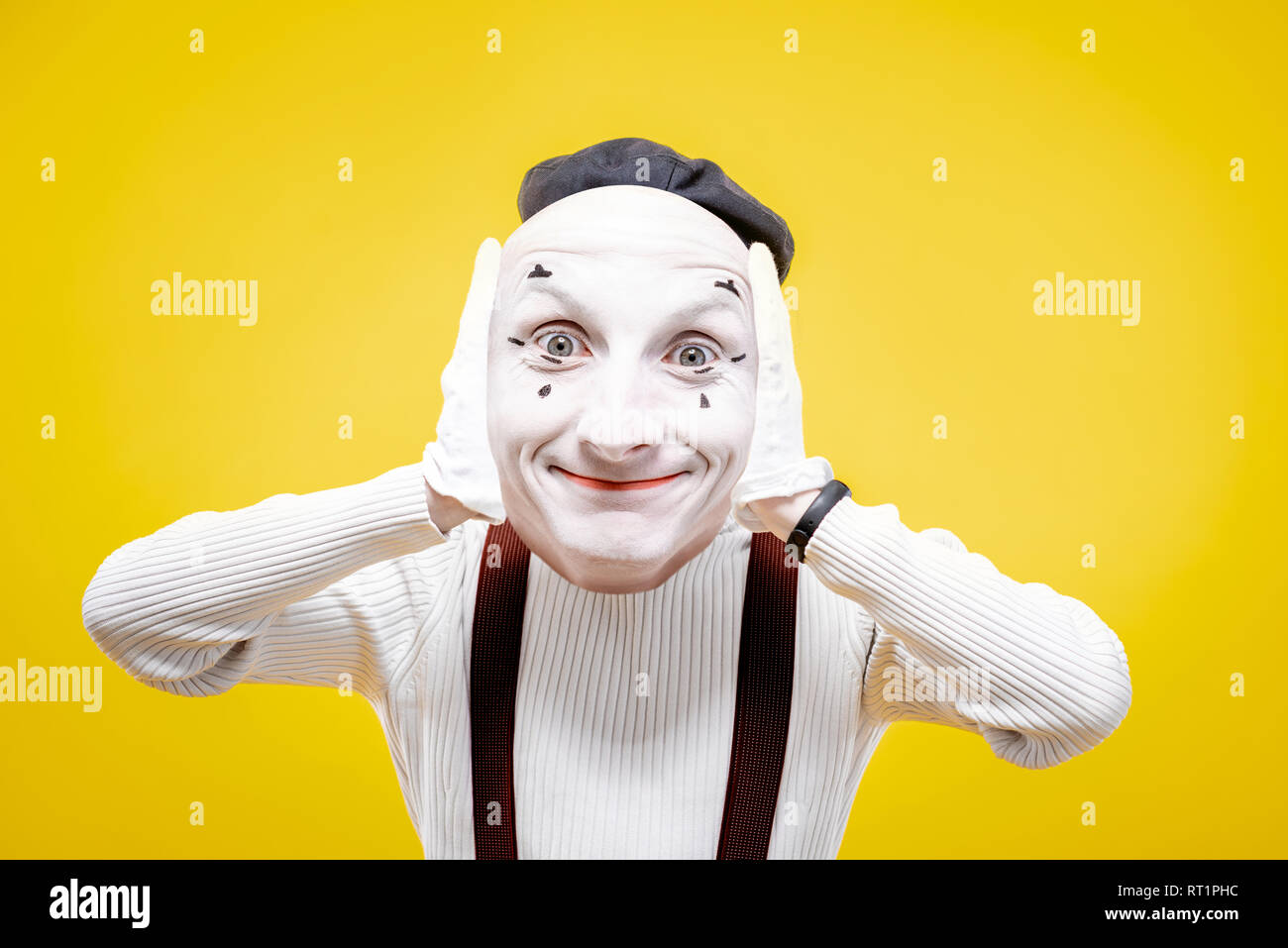 Pantomime actor holding facial mask with positive emotion on the yellow ...
