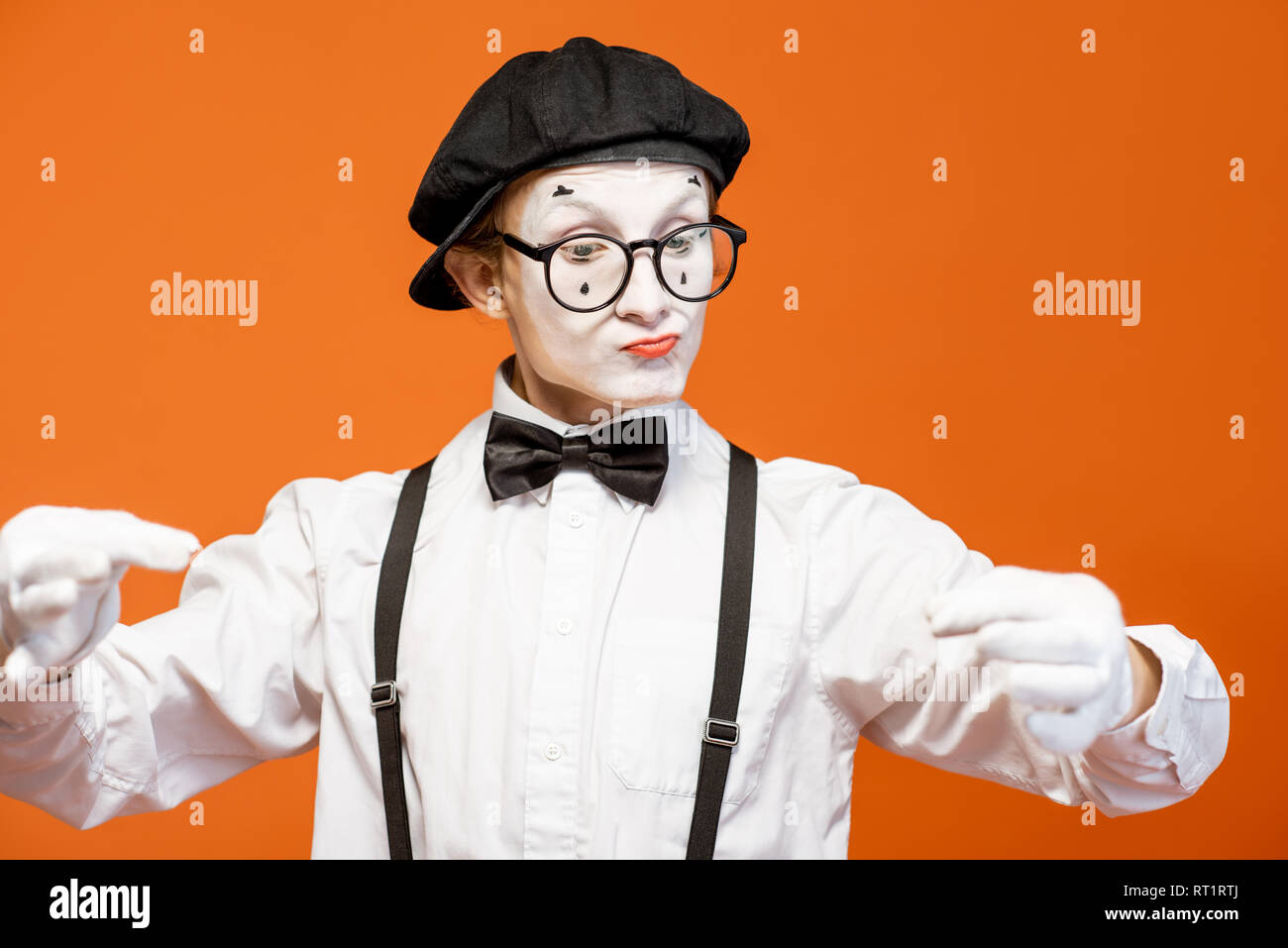 Portrait of a pantomime with white facial makeup in eyeglasses showing ...
