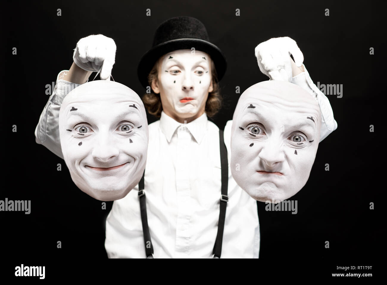 Portrait of a pantoomime holding two facial masks with different ...