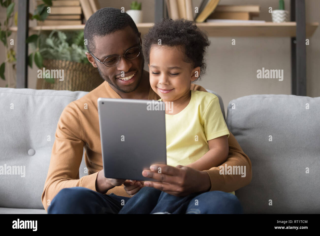 Happy african dad and little son using tablet at home Stock Photo - Alamy