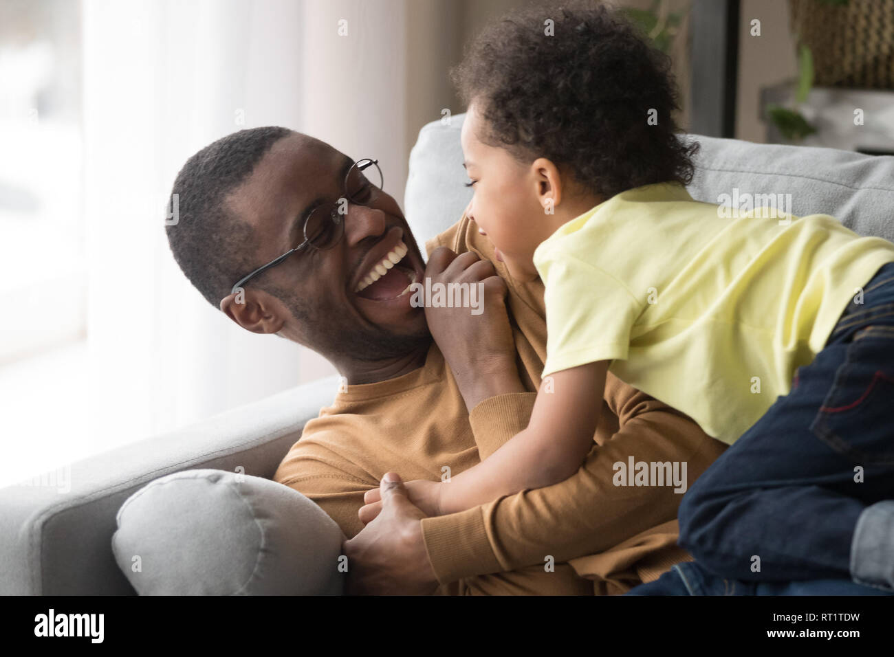 Happy african dad laughing playing with little toddler son together ...