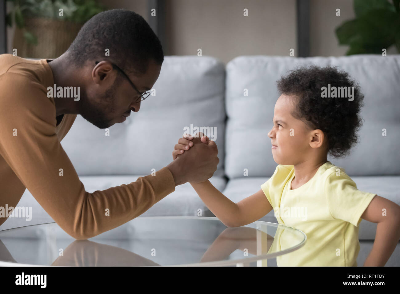 African dad and kid son with funny angry faces armwrestling Stock Photo ...