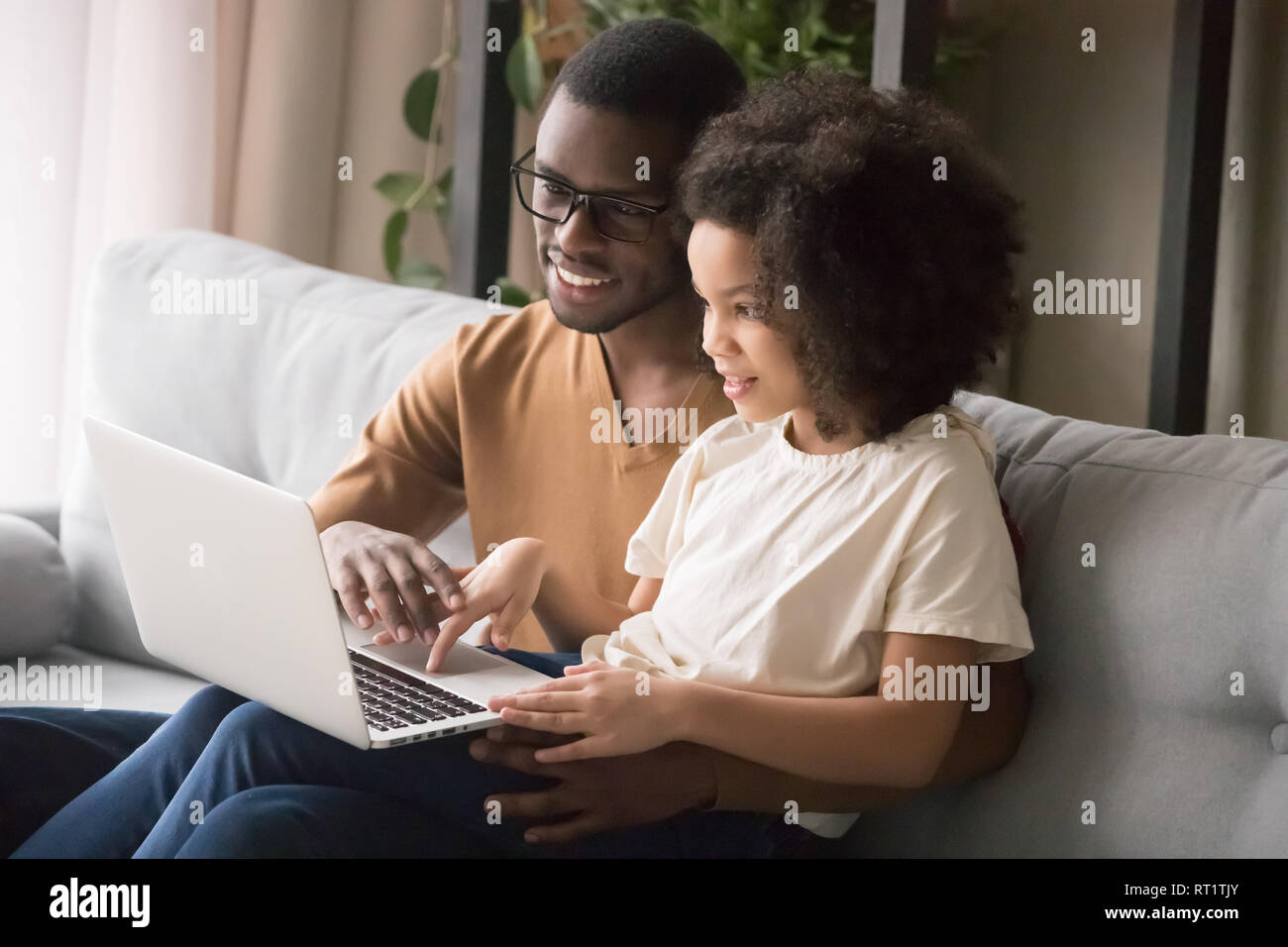African dad and child daughter using laptop computer at home Stock ...