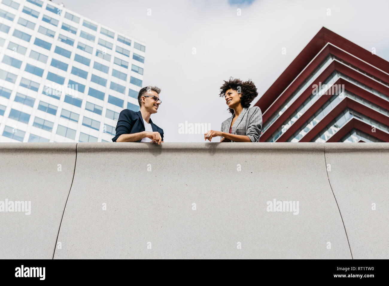 Two colleagues talking outside office building Stock Photo - Alamy