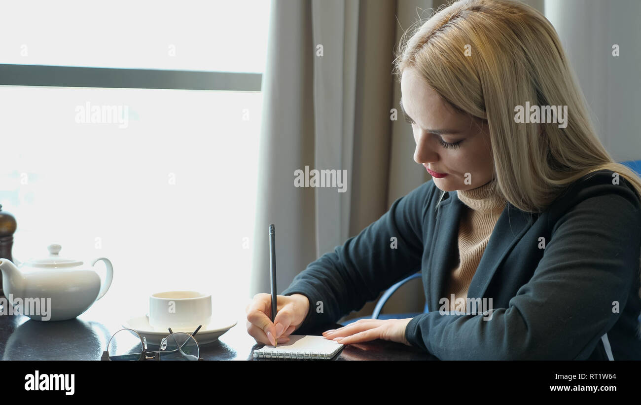 Beautiful young girl making notes in cafe Stock Photo - Alamy
