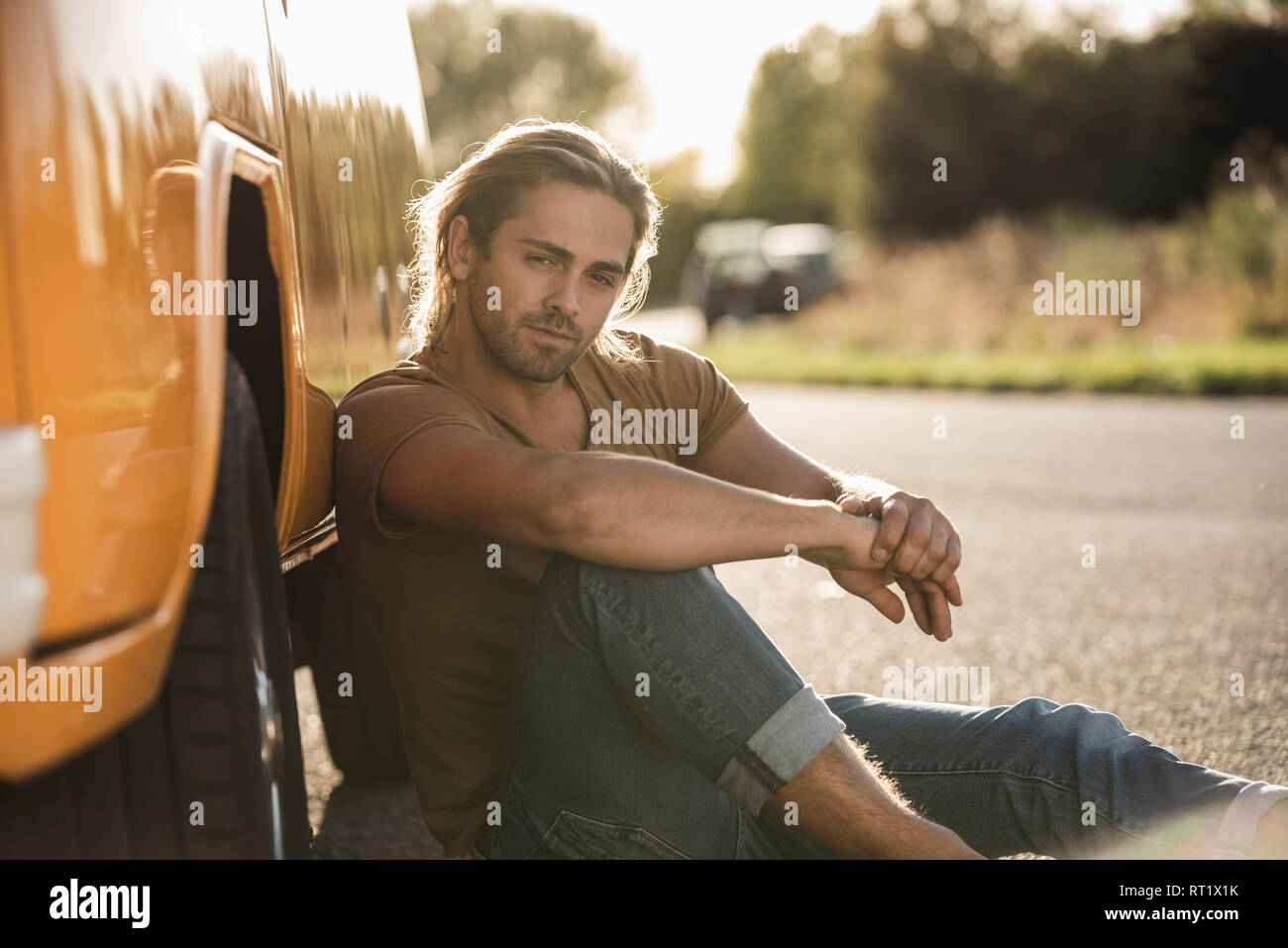 Young man on a road trip with his camper, relaxing at the roadside ...