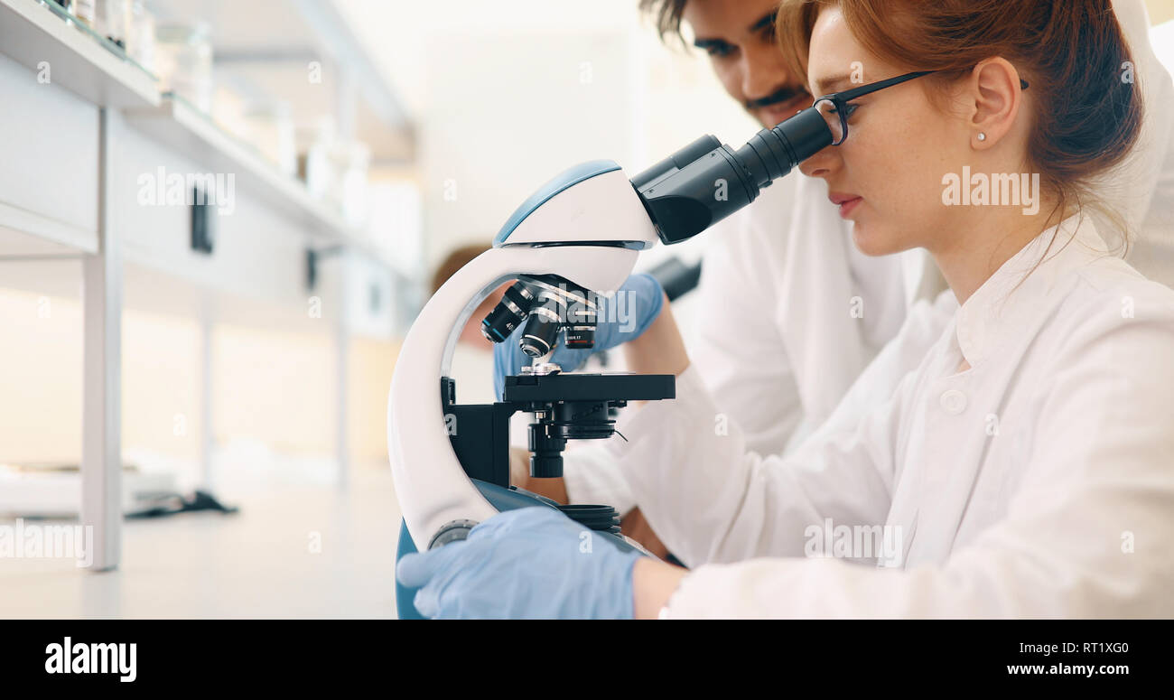 Young scientist looking through microscope in laboratory Stock Photo ...
