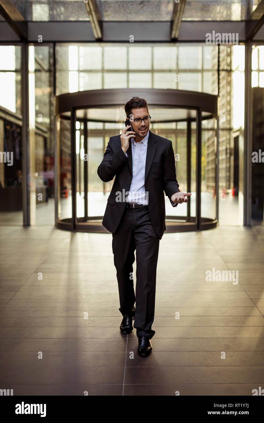 Businessman on cell phone in foyer of an office building Stock Photo ...