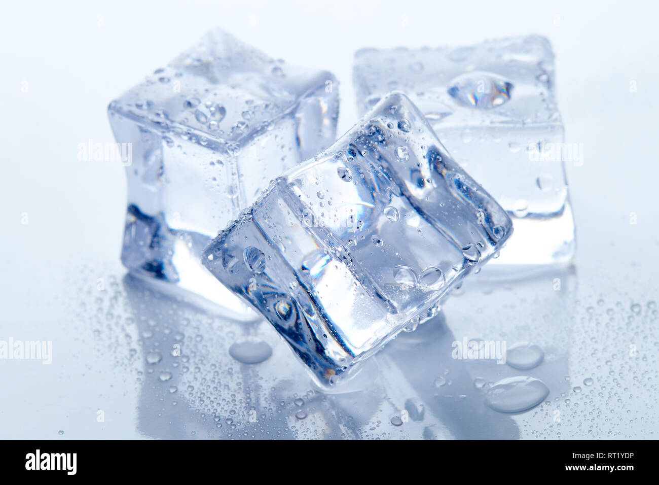 Wet square ice cubes on reflective light blue background Stock Photo ...