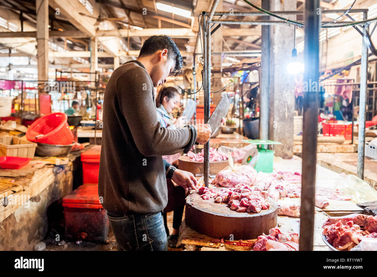 A butcher chops meat at his stall in a busy indoor market in Phnom Penh ...