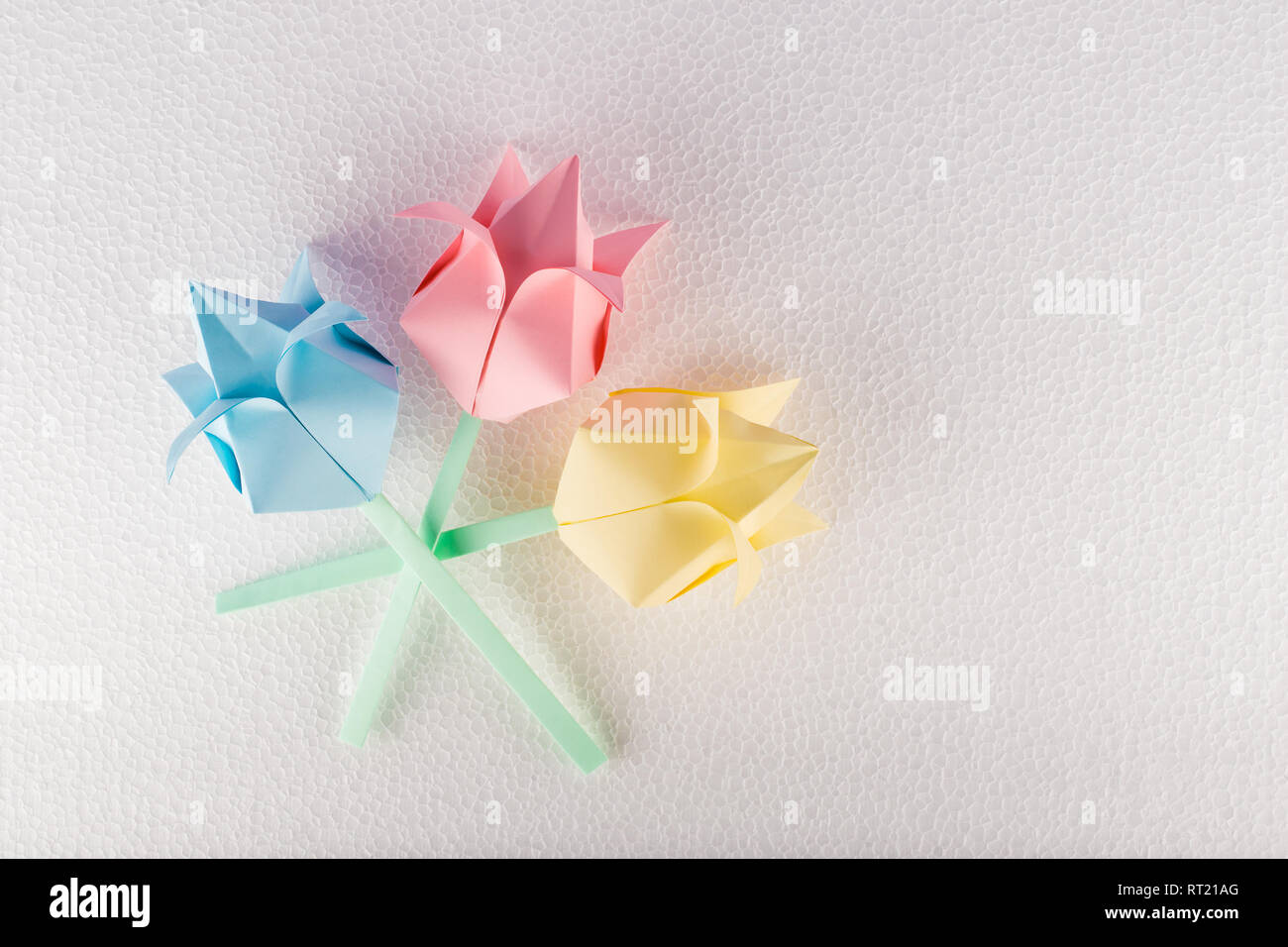 Three origami flowers on white textured background Stock Photo - Alamy