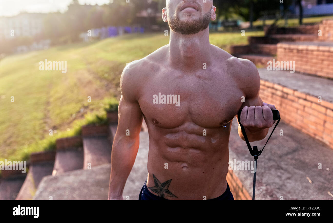 Mid-section of barechested muscular man exercising with expander ...