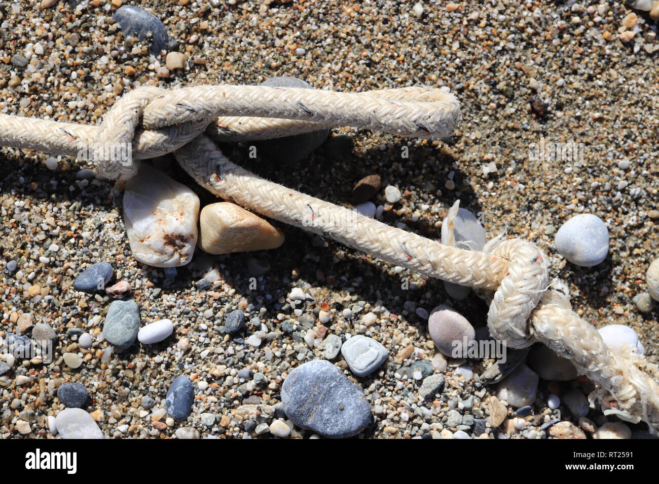 Rope with stone on sand beach Stock Photo - Alamy