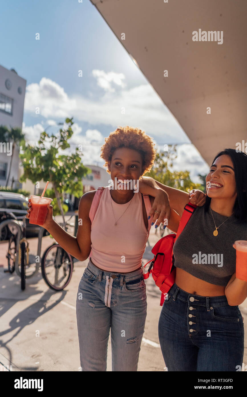 USA, Florida, Miami Beach, two happy female friends having a soft drink ...