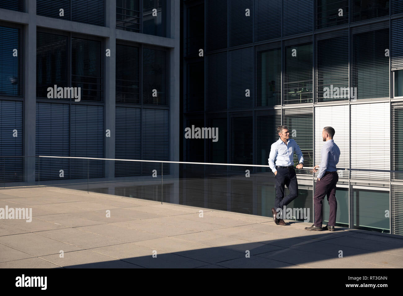 Two businessmen talking outside office building Stock Photo - Alamy