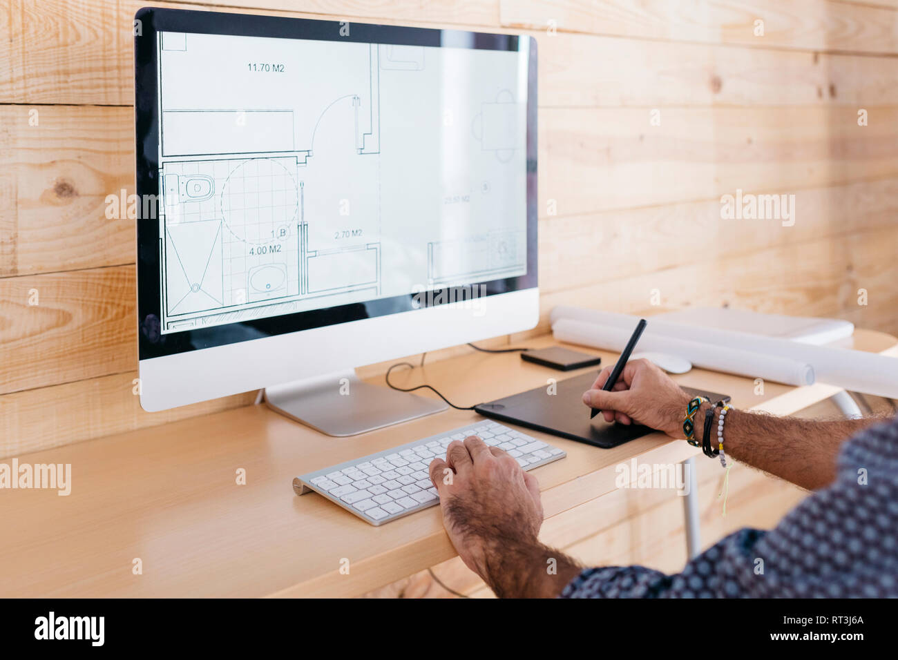 Close-up of man working on floor plan at home using the computer and ...
