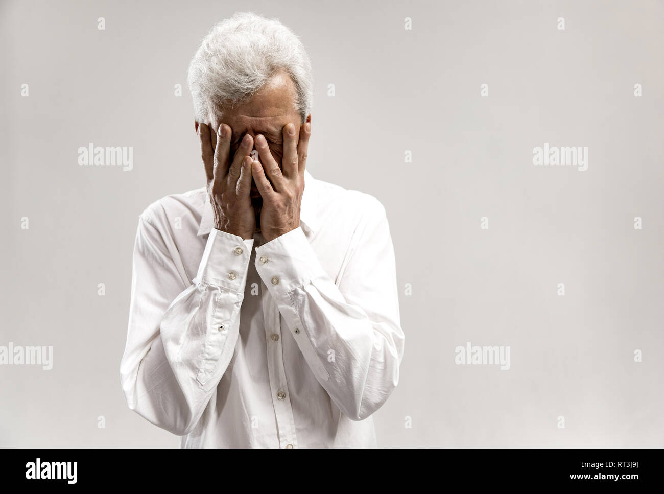 Portrait of upset old man covering face while crying. Isolated on grey ...