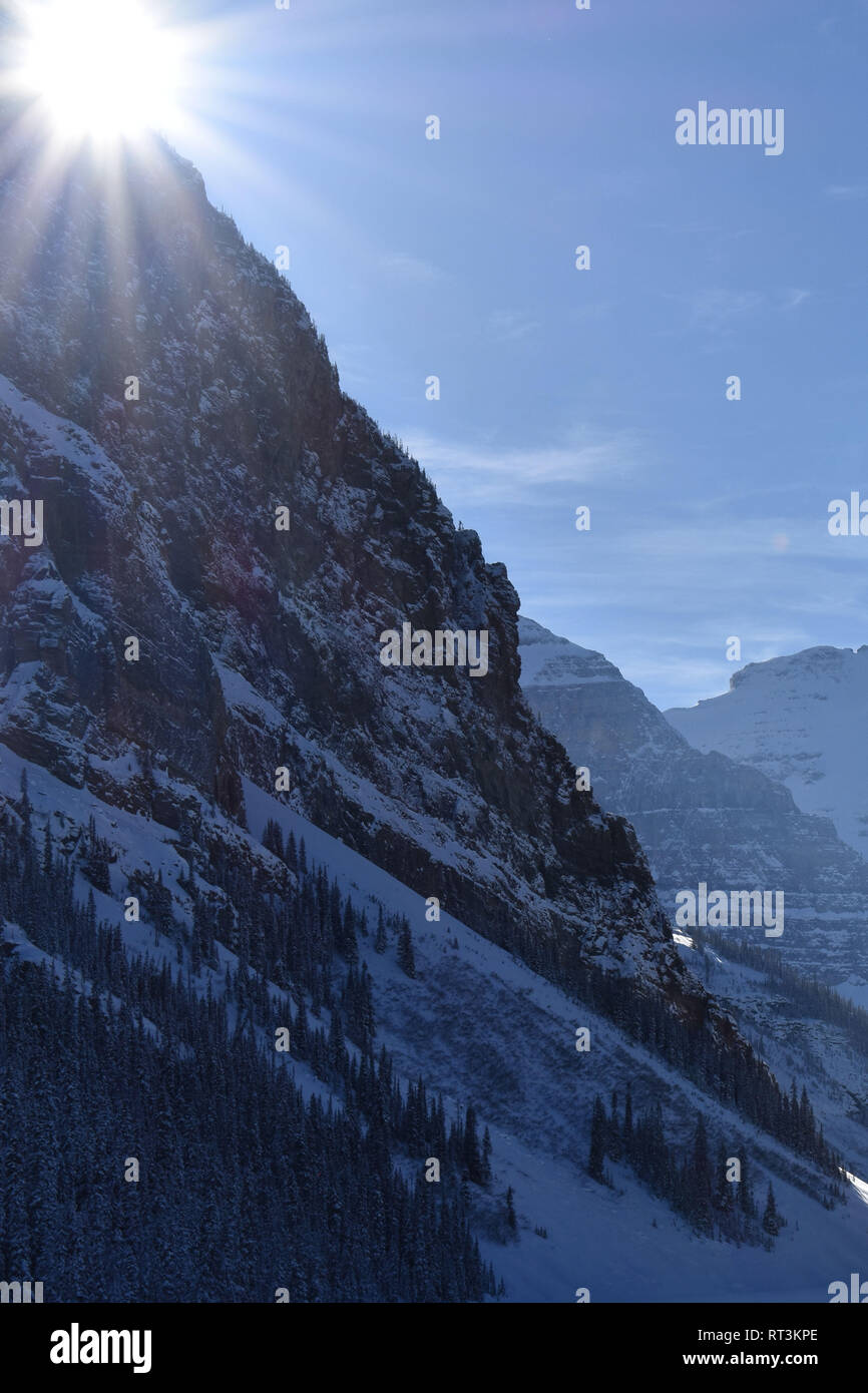 Sun over rocky mountain at a sharp incline in the winter Stock Photo ...