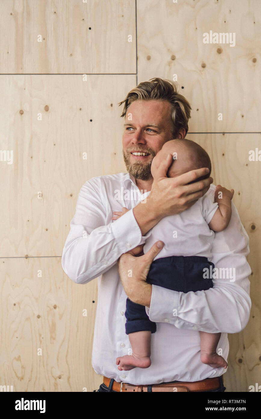 Working father standing in office, holding his son Stock Photo - Alamy
