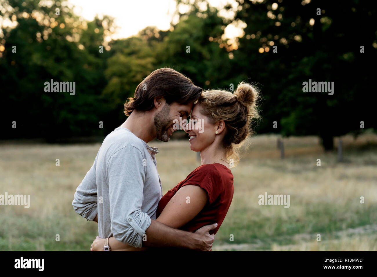 Happy couple in nature, standing face to face, caressing each other ...