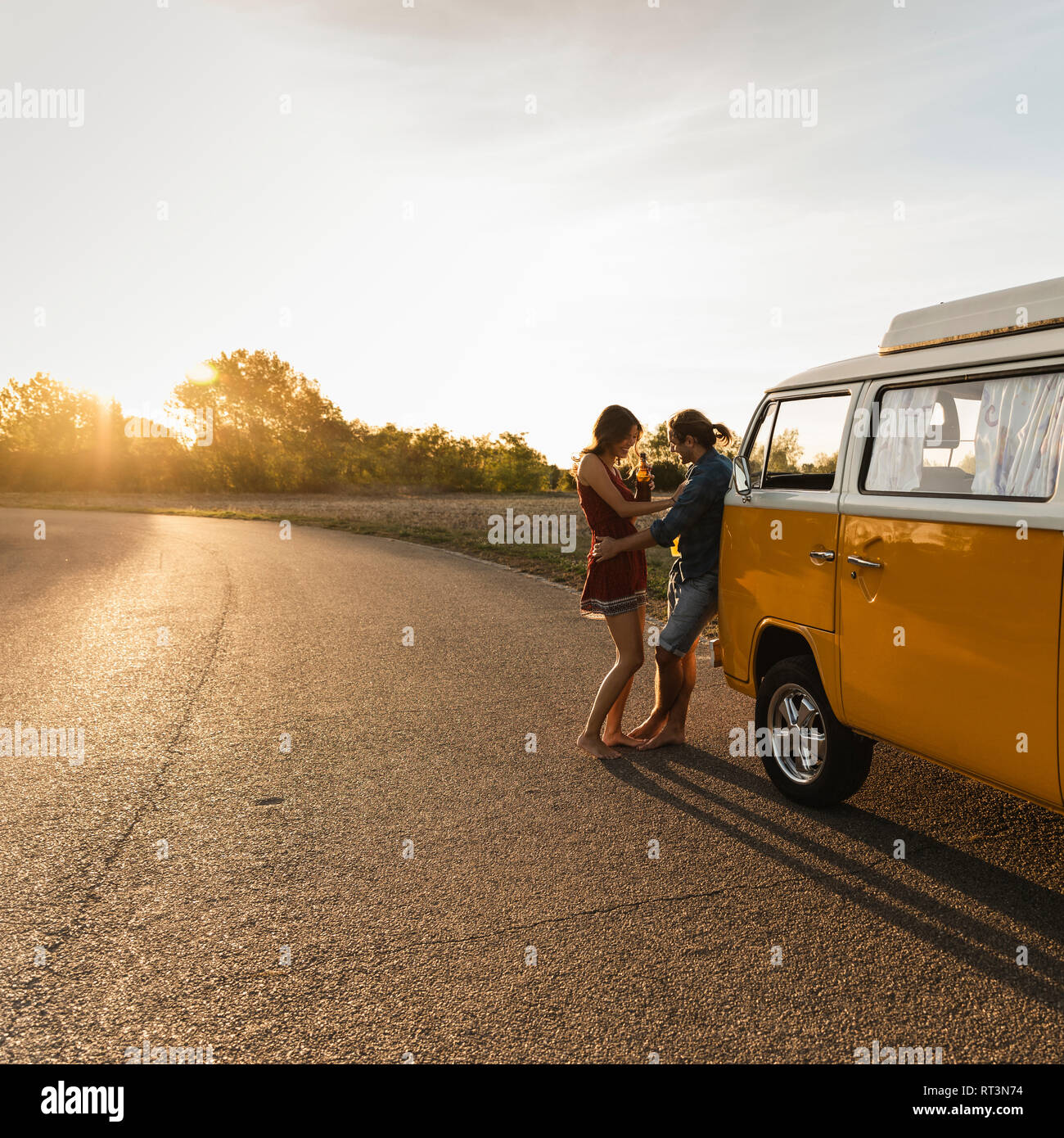Happy couple taking a break on their road trip, having a drink at ...