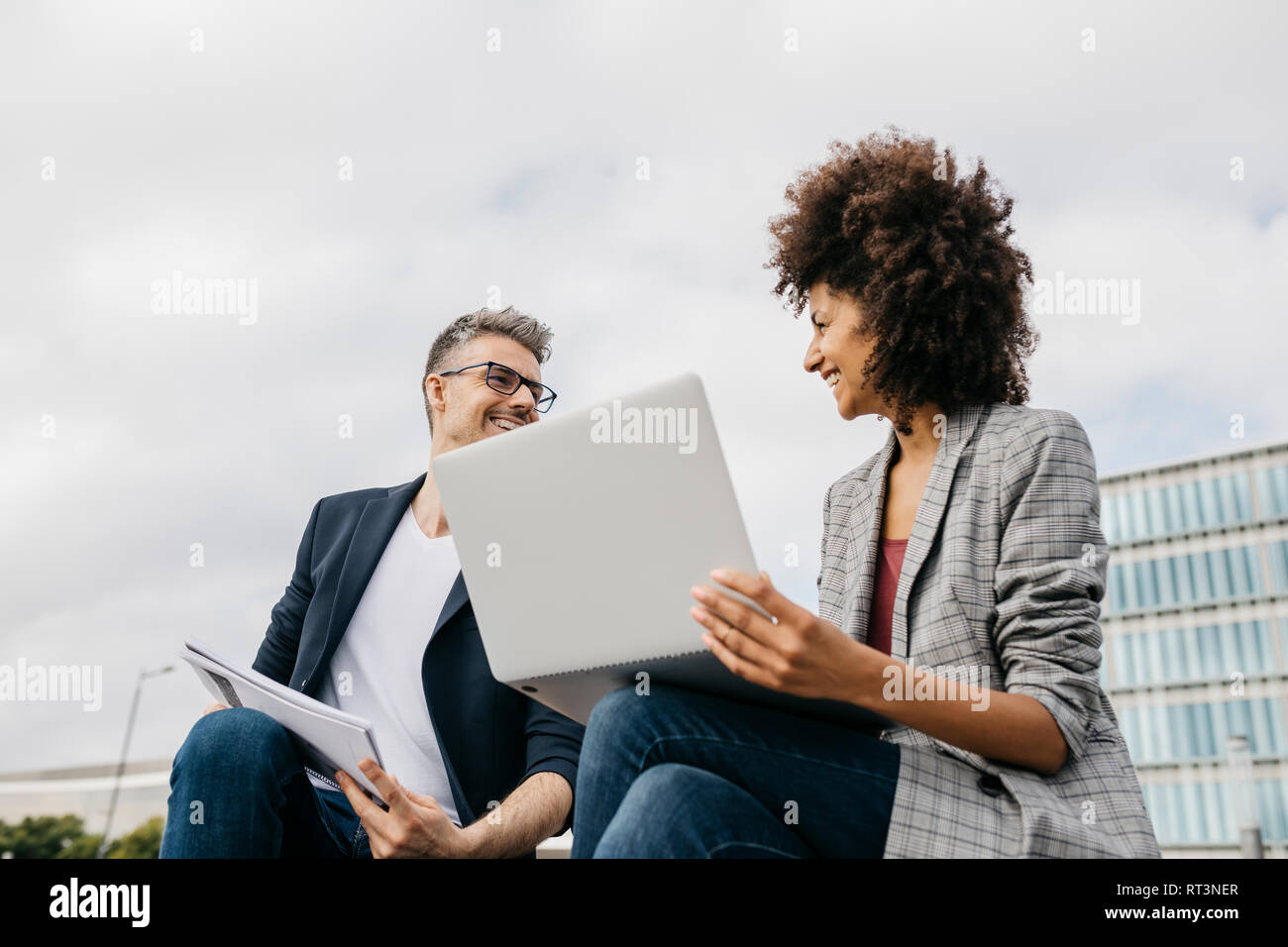 Two happy colleagues working together outside office building Stock ...