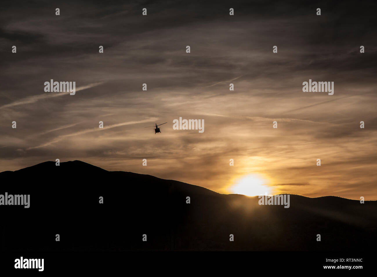 Helicopter flying into the sun at dusk Stock Photo - Alamy