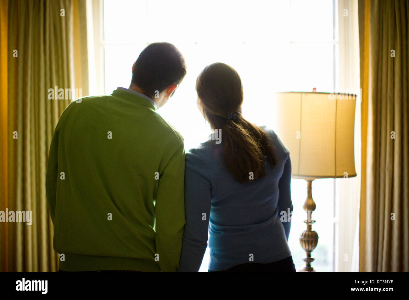Couple looking out window together Stock Photo - Alamy