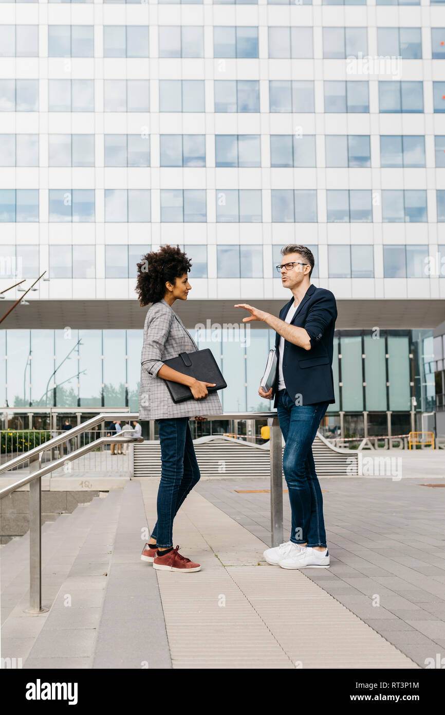 Two colleagues talking outside office building Stock Photo - Alamy