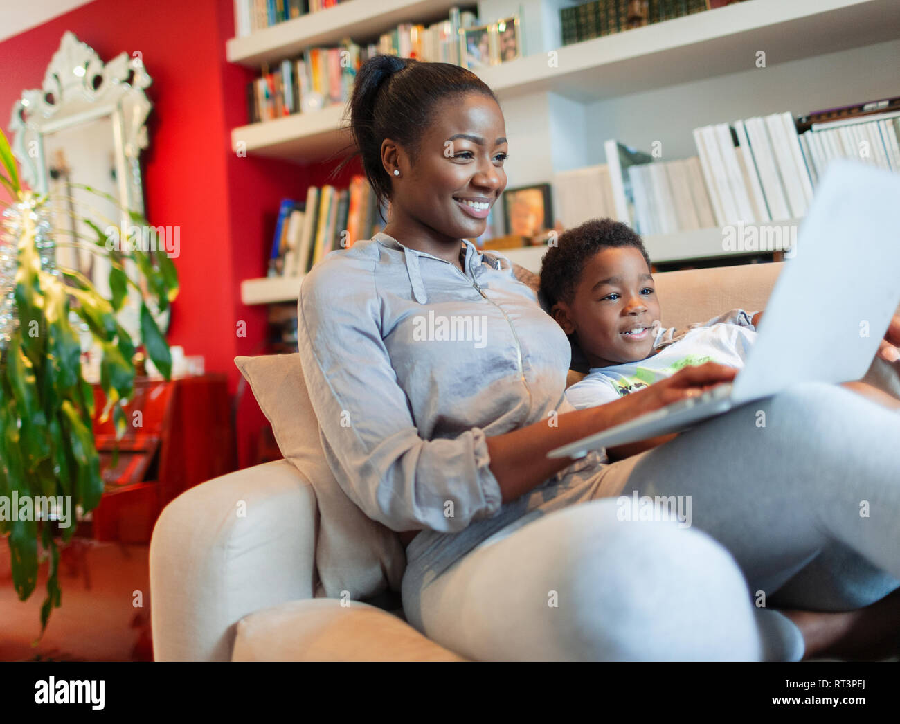 Mother and son using laptop on living room sofa Stock Photo - Alamy