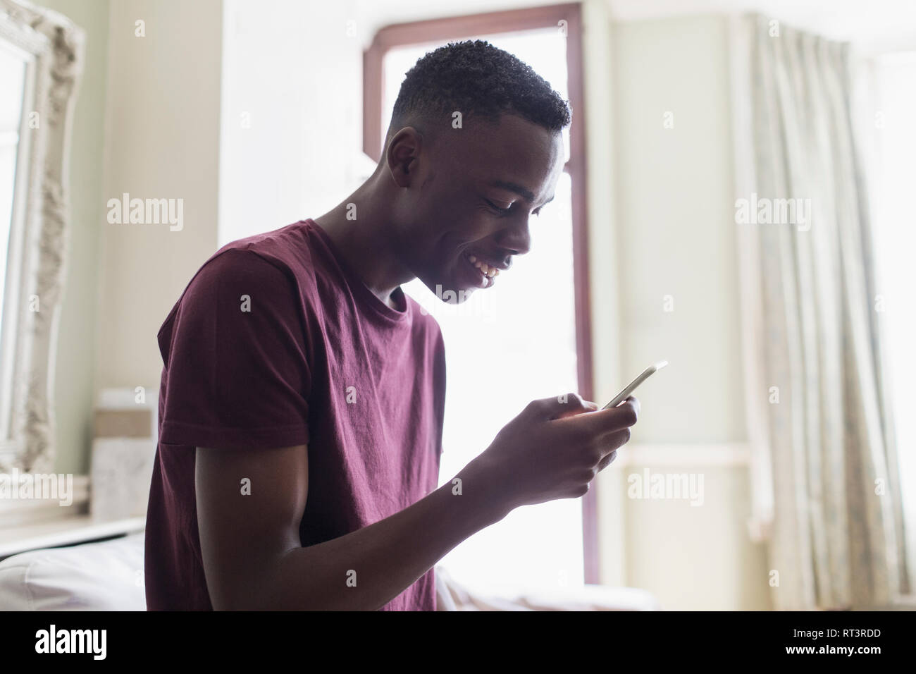 Smiling teenage boy texting with smart phone Stock Photo - Alamy