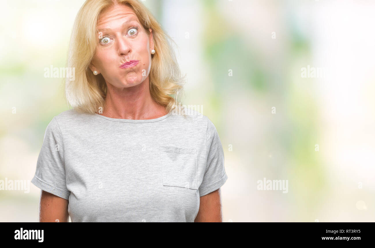 Middle age blonde woman over isolated background puffing cheeks with ...