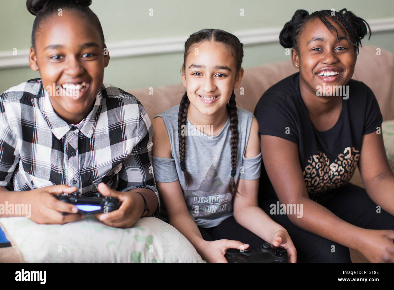 Portrait smiling tween girl friends playing video game on sofa Stock ...