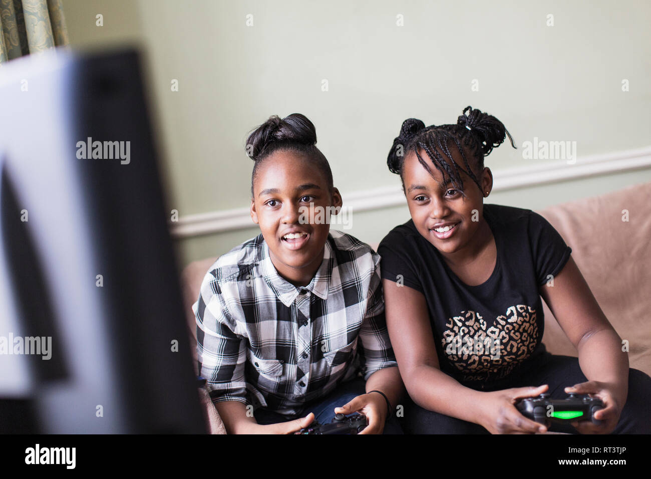 Tween girl friends playing video game in living room Stock Photo - Alamy