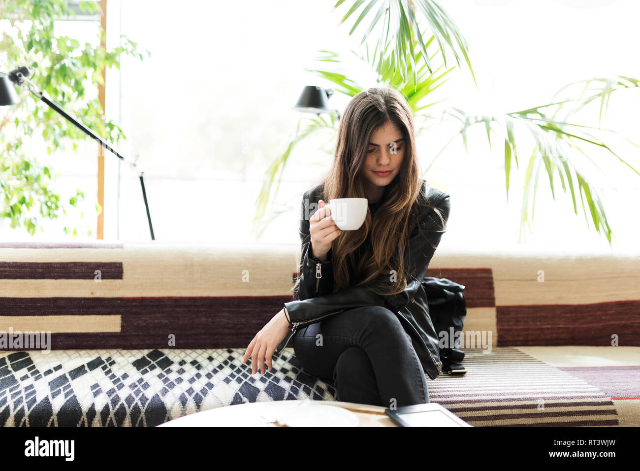 Young woman sitting in a cafe drinking coffee Stock Photo - Alamy