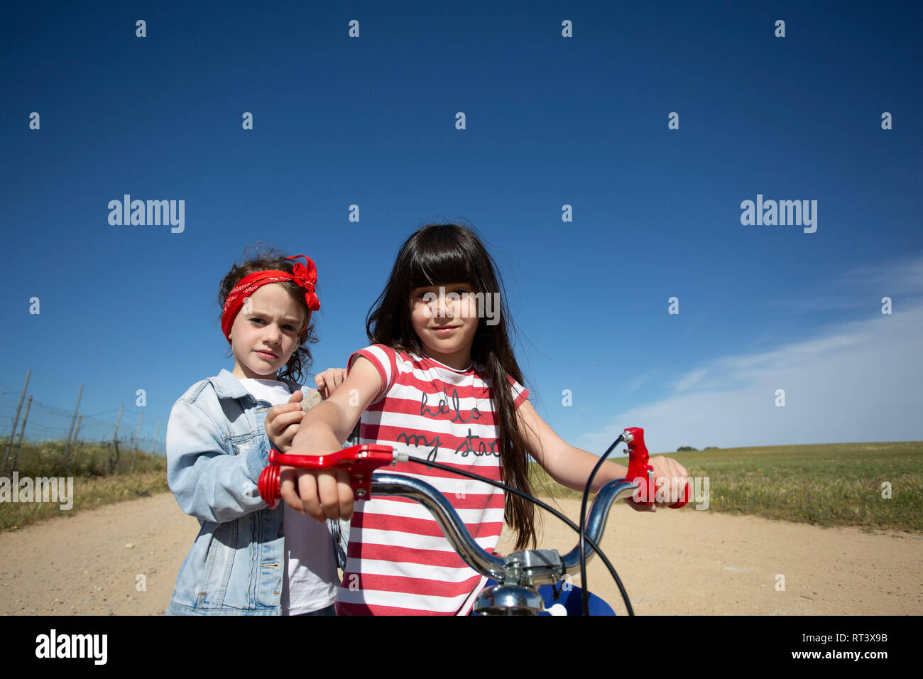 Two girls with bicycle on path in remote landscape Stock Photo - Alamy