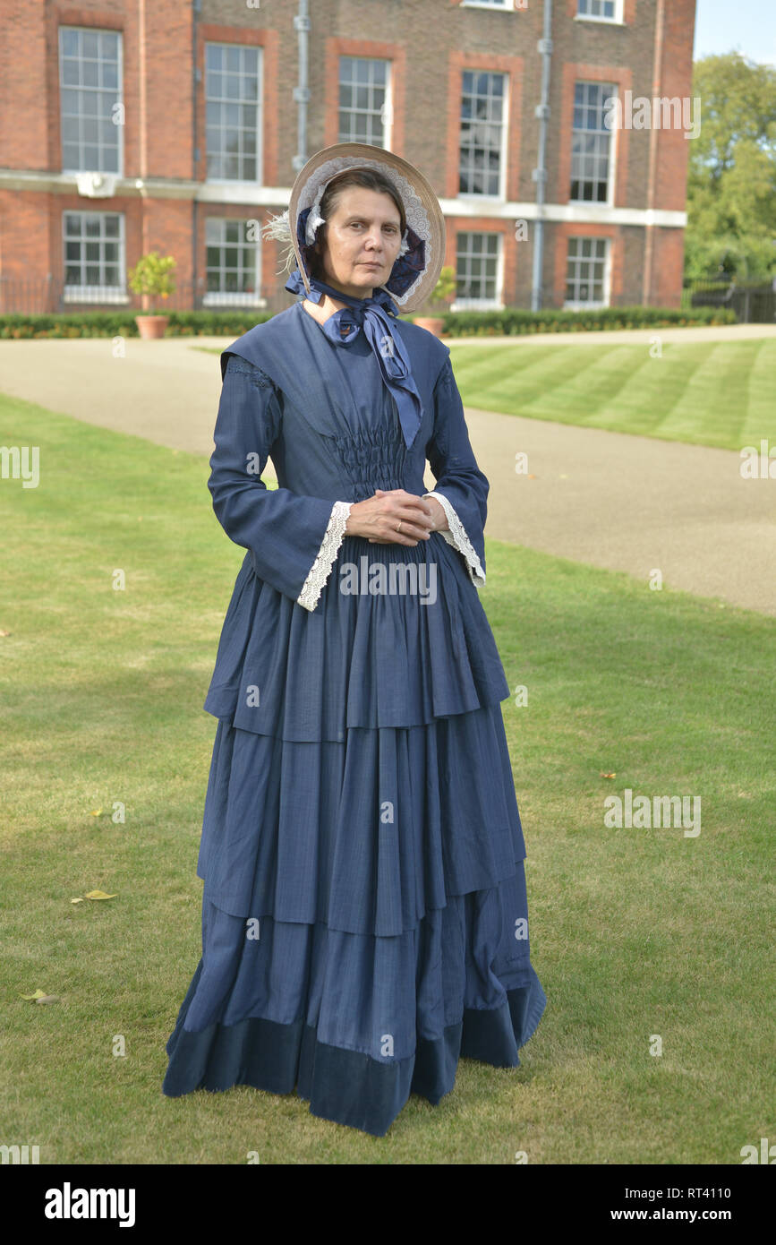 An old stern looking Victorian woman in a bonnet stands in front of ...