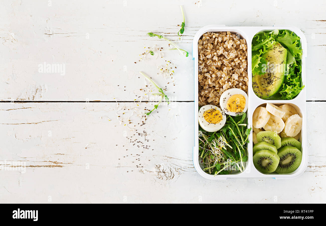Lunch box with boiled eggs, oatmeal, avocado, micro greens and fruits ...