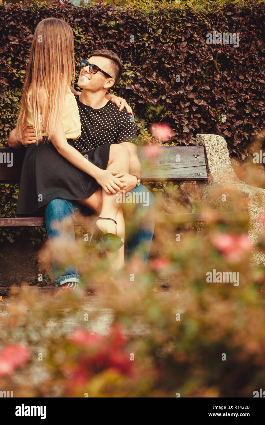 Love romance flirt dating concept. Affectionate couple sitting on bench ...