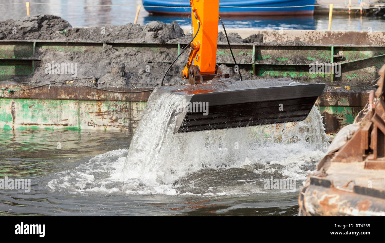 Excavator shovel digging in sand from water. Building construction ...