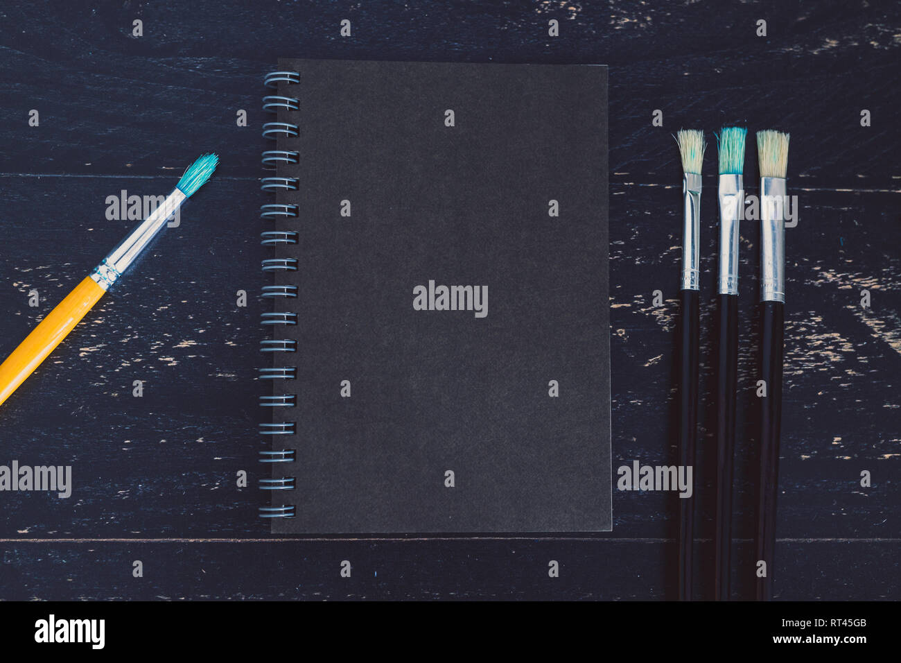 black notepad on dark desk with brushes, concept of creativity and ...