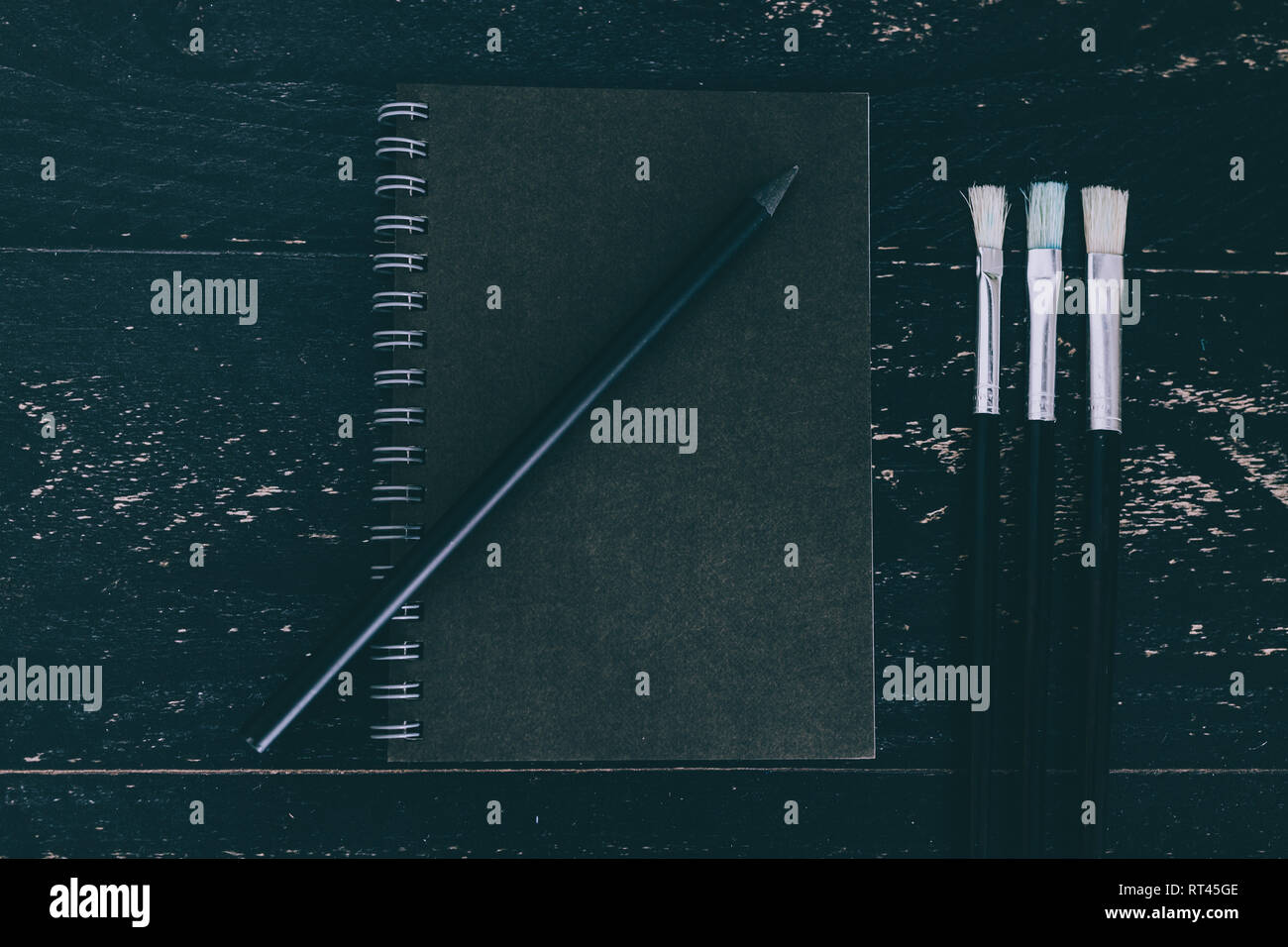 black notepad on dark desk with brushes, concept of creativity and ...