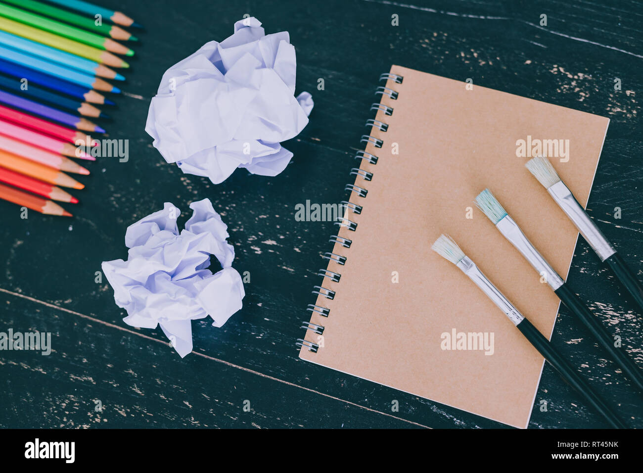 desk with mixed art supplies including coloured pencils notepads and ...