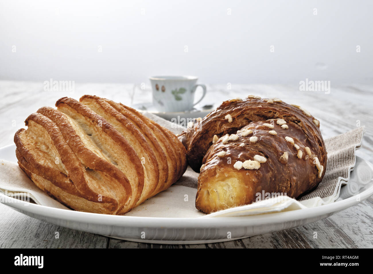 due brioche nel piatto fronte con tazza caffè Stock Photo - Alamy