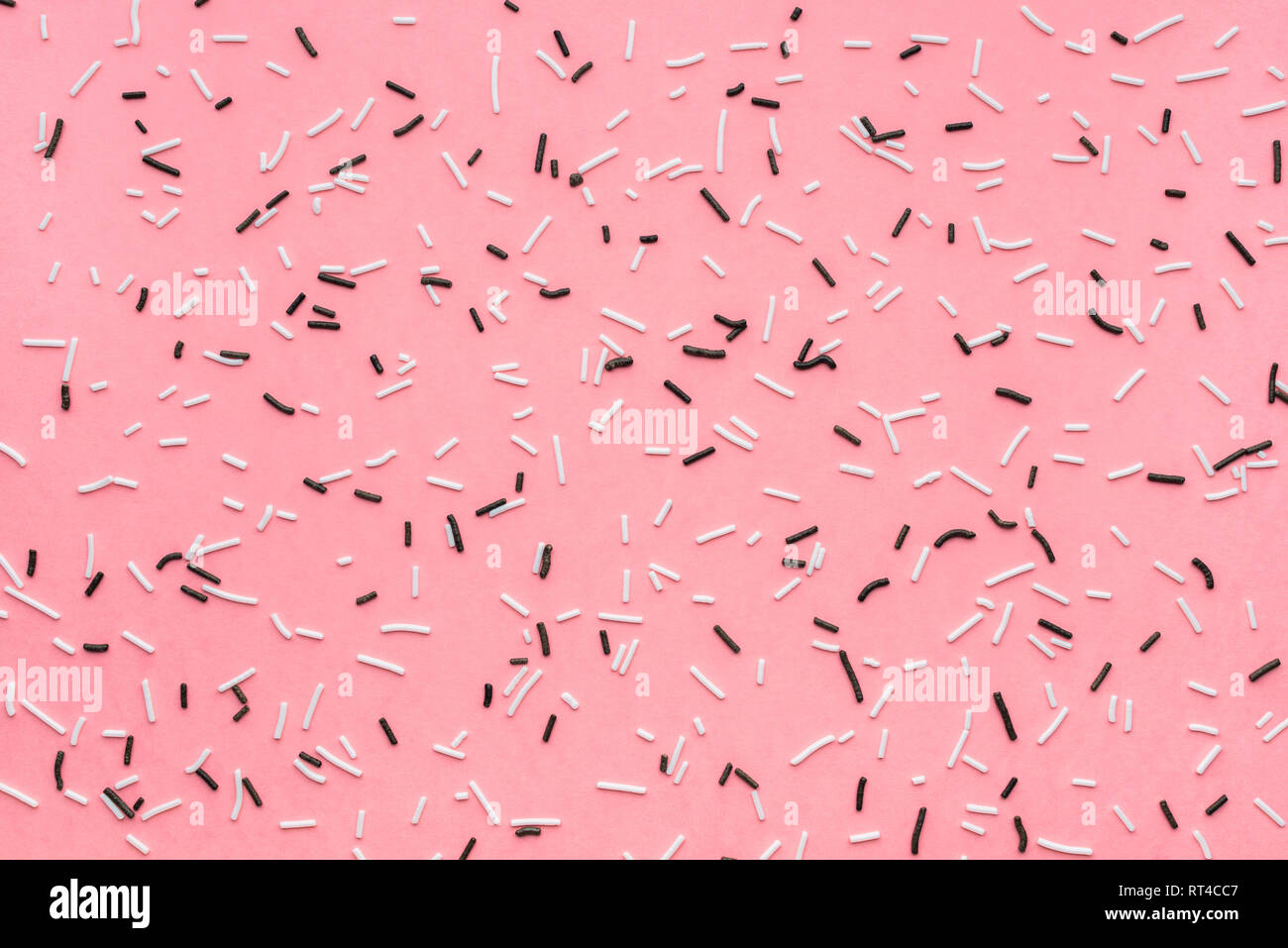 trendy pattern of white and black sprinkles over pink background, sugar ...