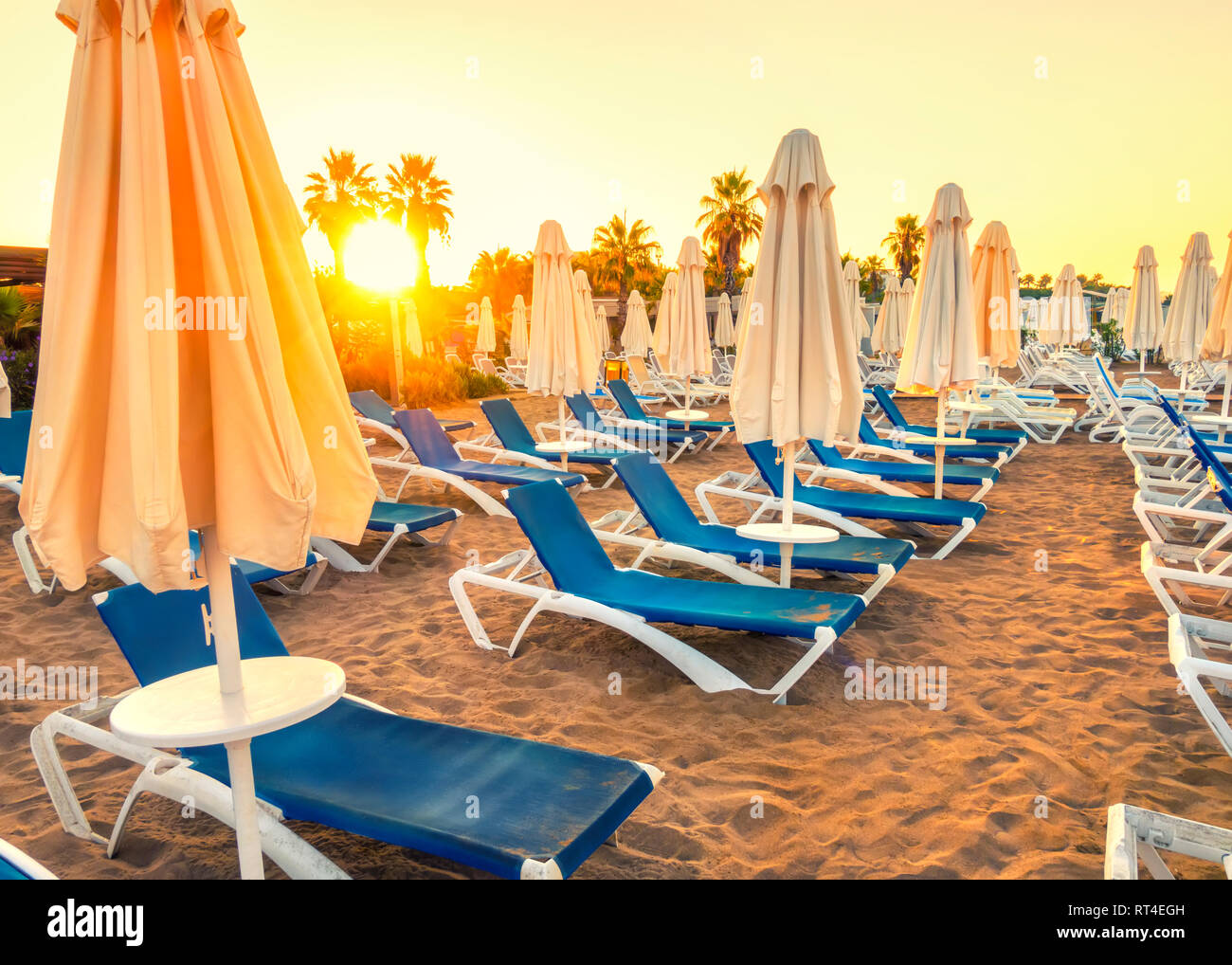 sandy beach without people and with sun loungers, folded umbrellas ...