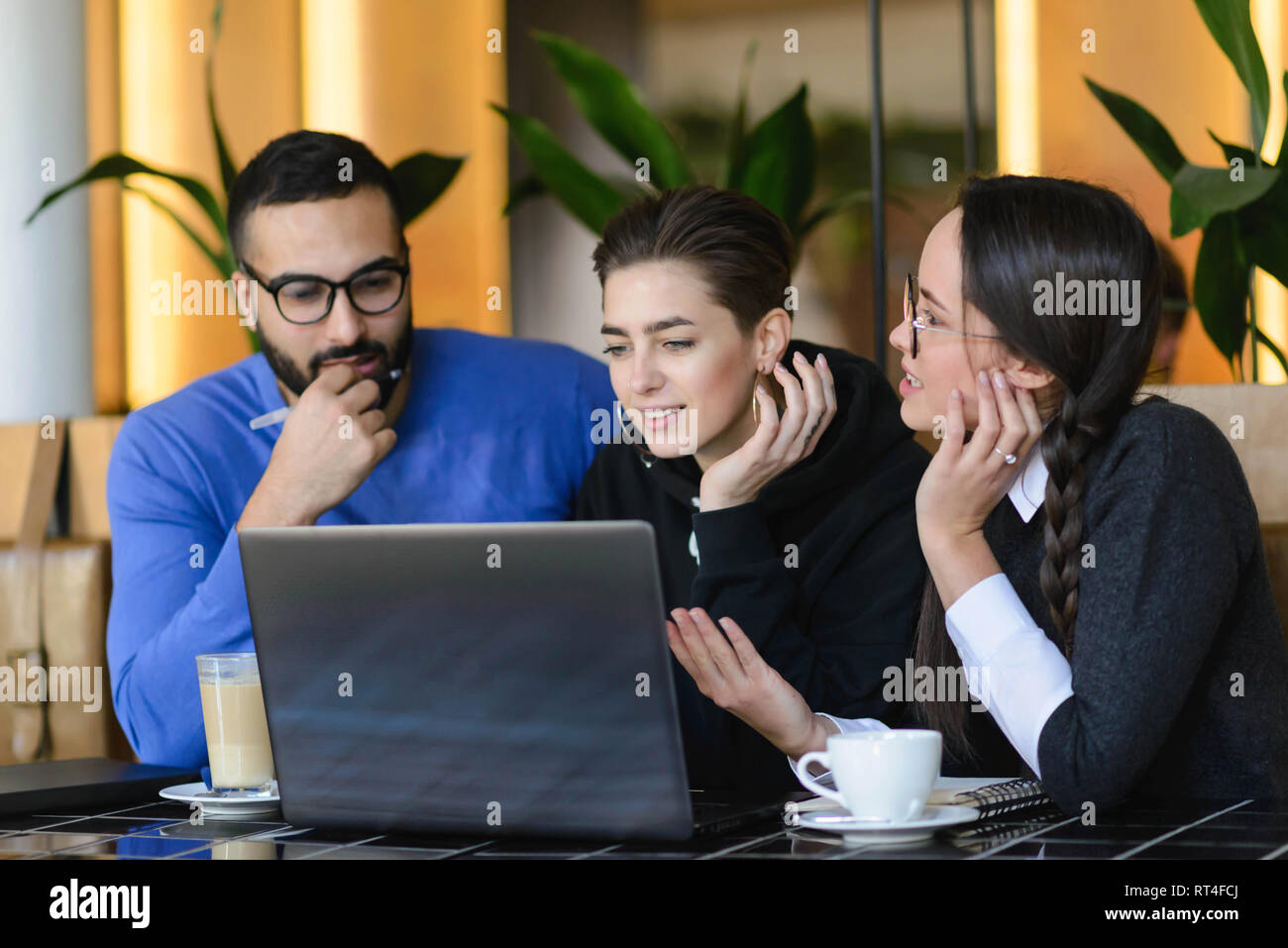 Happy smiling diverse friends doing homework and using laptop together ...