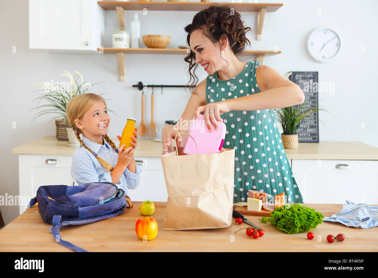 Beautiful brunette mother and her daughter packing healthy lunch and ...