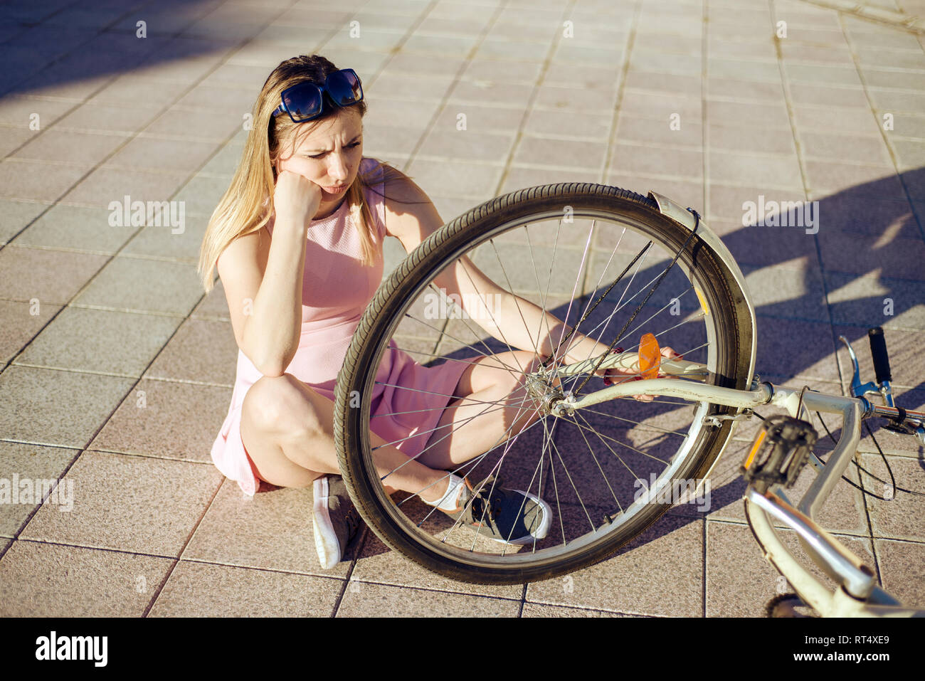 girl dropped and broke the bicycle. emotion is upset and does not know ...